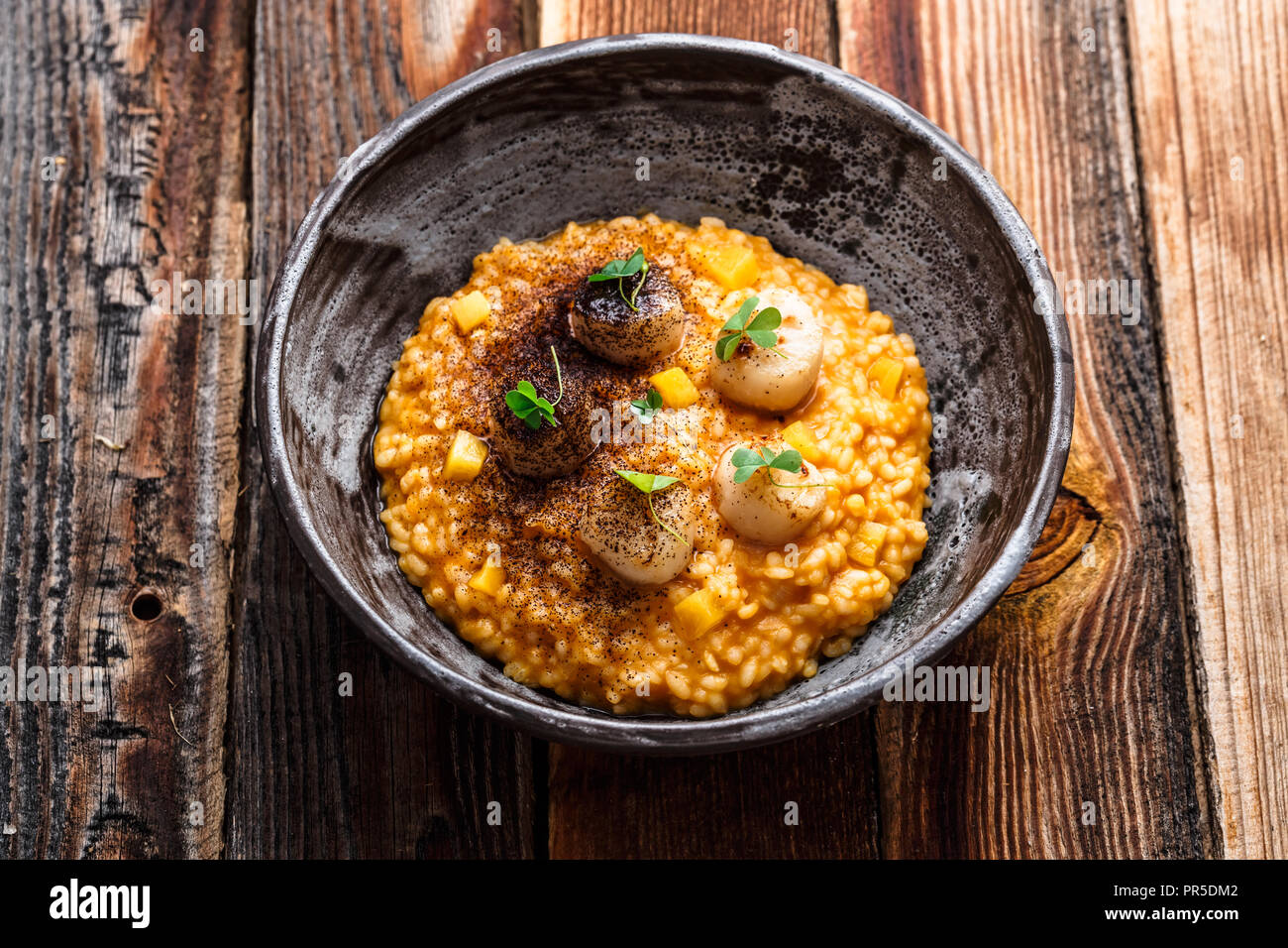 Pumpkin risotto with scallops in a bowl, wooden background, copy space ...