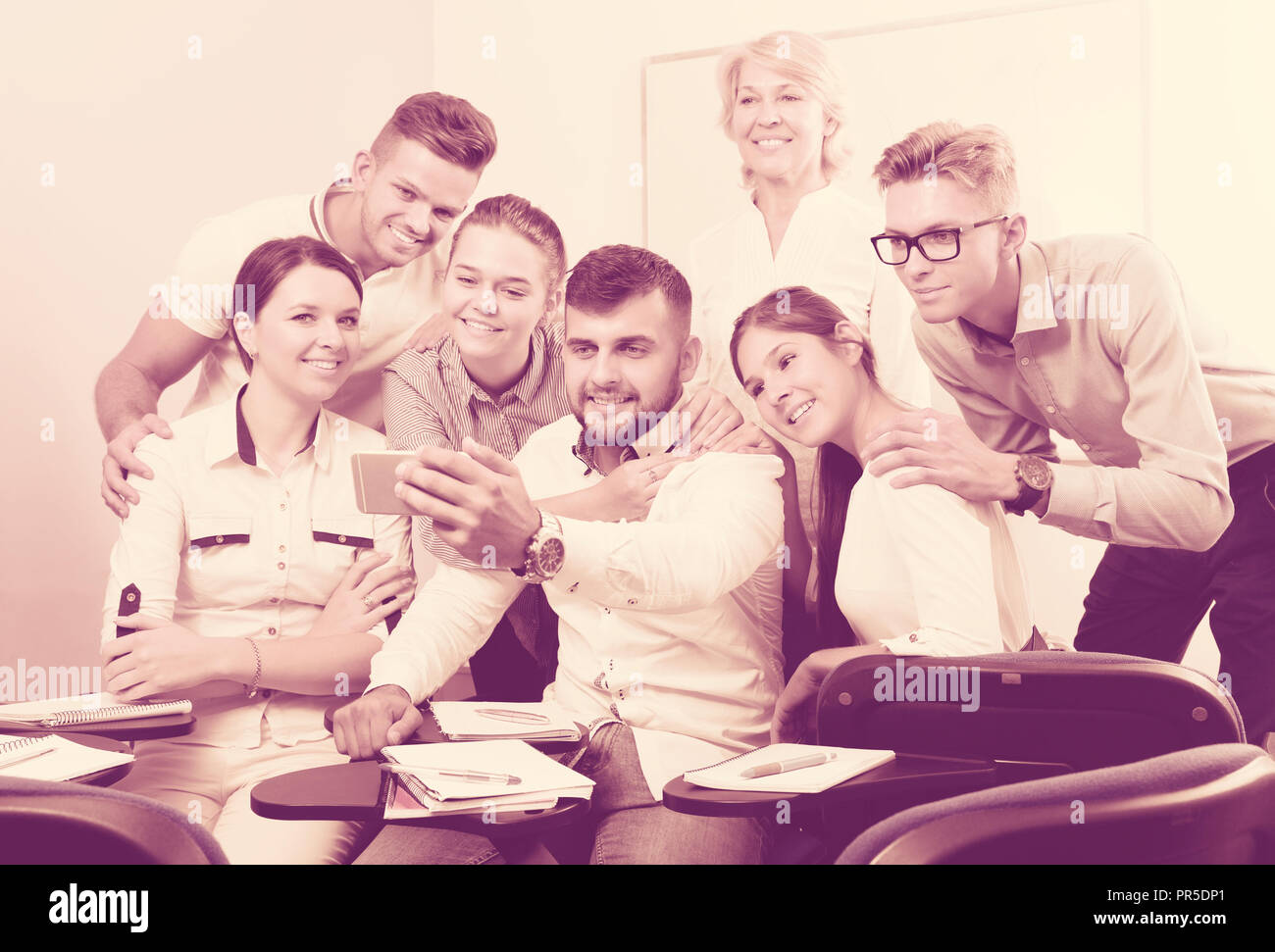 happy young students and female professor taking selfie in auditorium ...