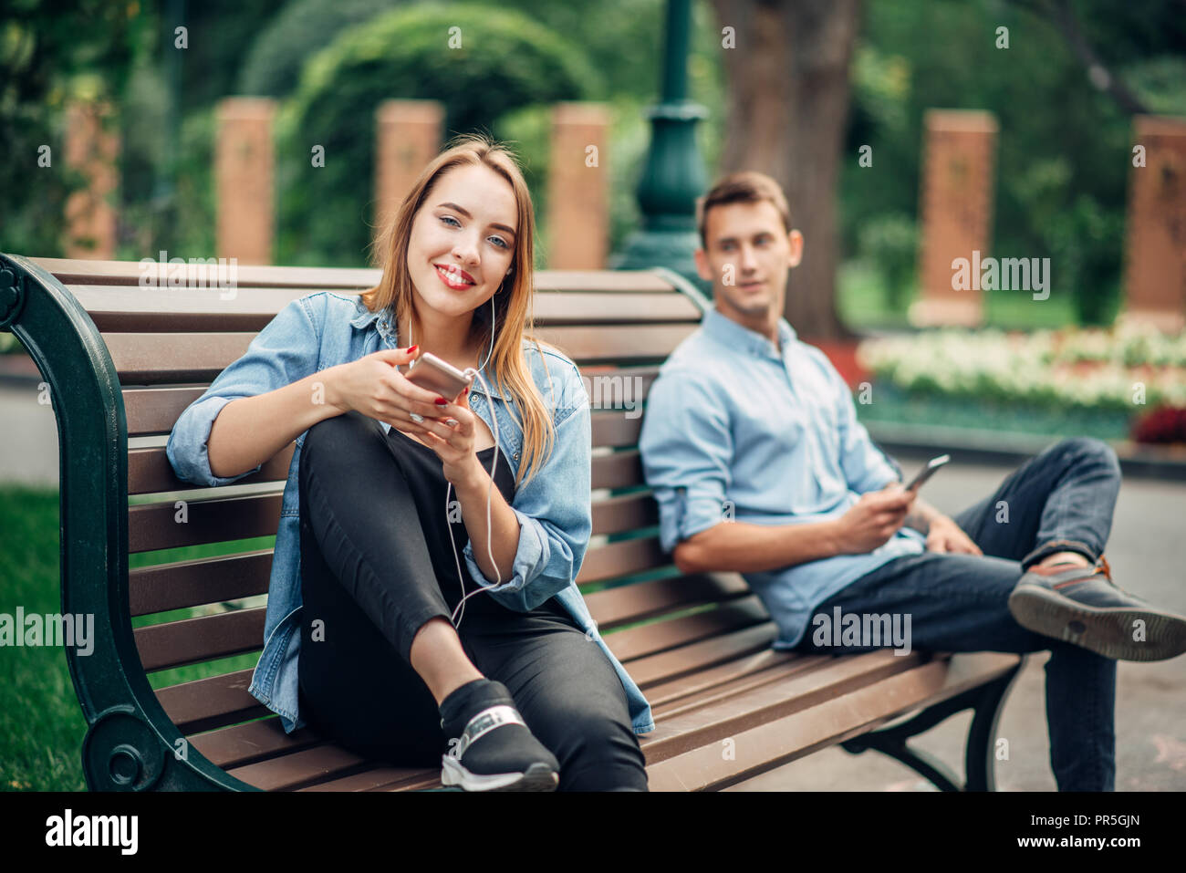 Phone addiction, couple ignoring each other on the bench in park. Man ...