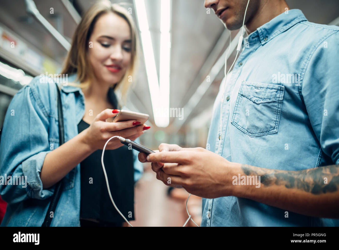 Young couple using phones in subway car, addiction problem, social ...