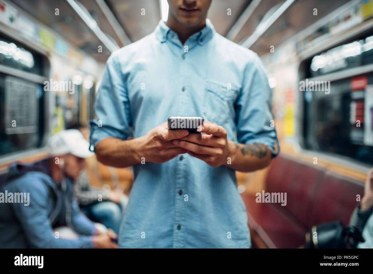Young man using phone in subway car, addiction problem, social addicted ...