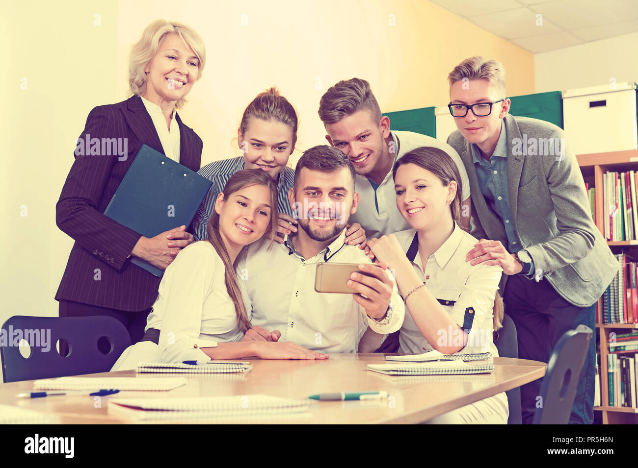 Group of students and female professor taking selfie in auditorium ...