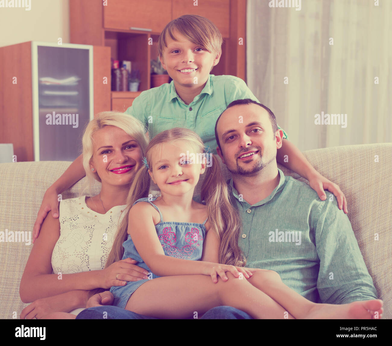 happy parents with two children posing in home interior Stock Photo - Alamy