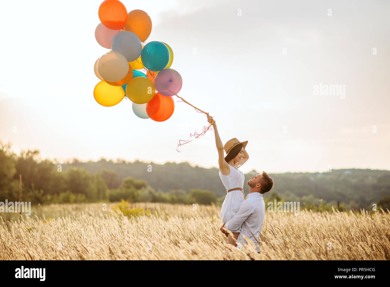 Love couple with balloons hugs in a rye field. Pretty woman on summer ...