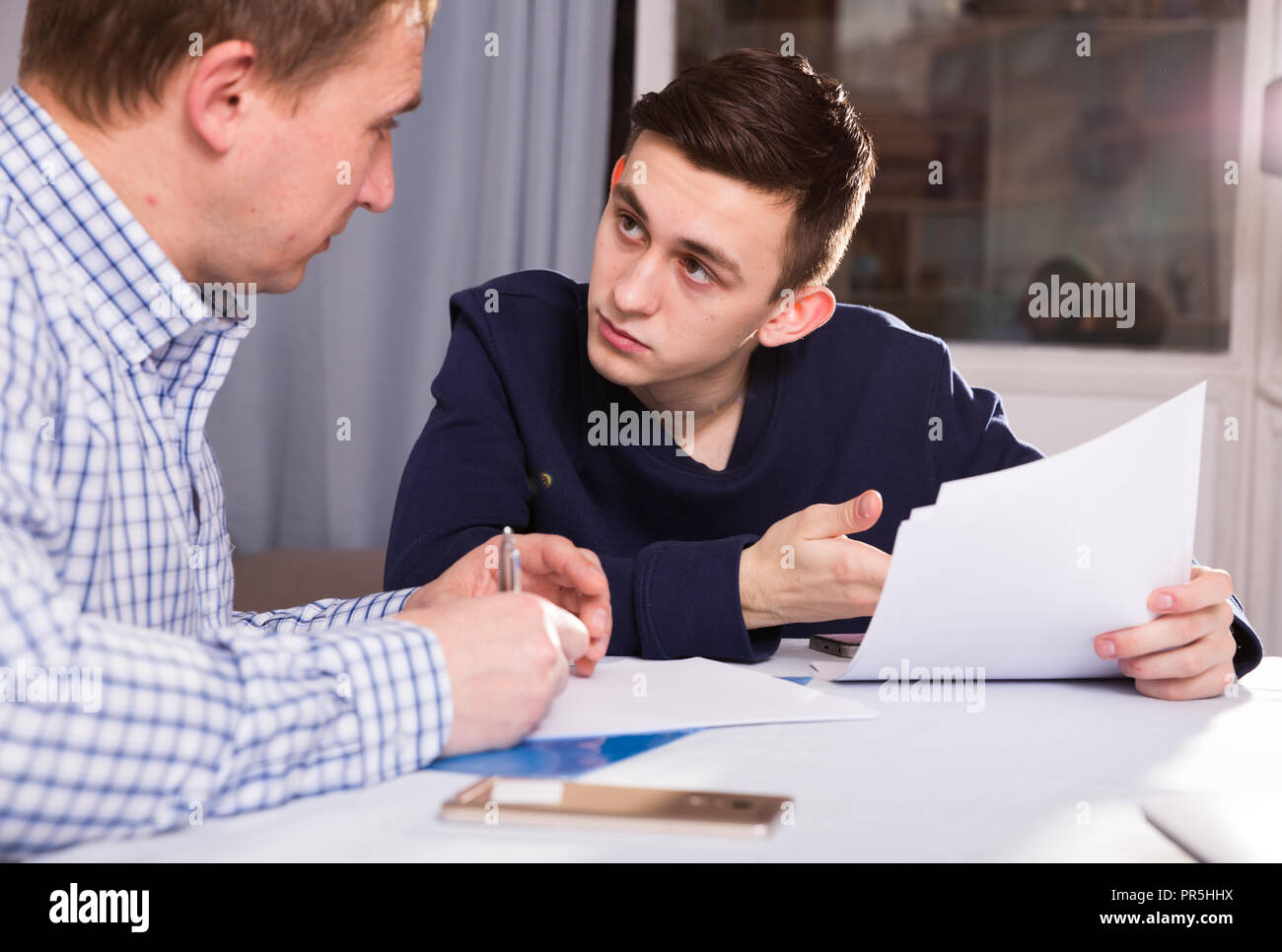 Tense guy with his father are working and reading documents at the home ...