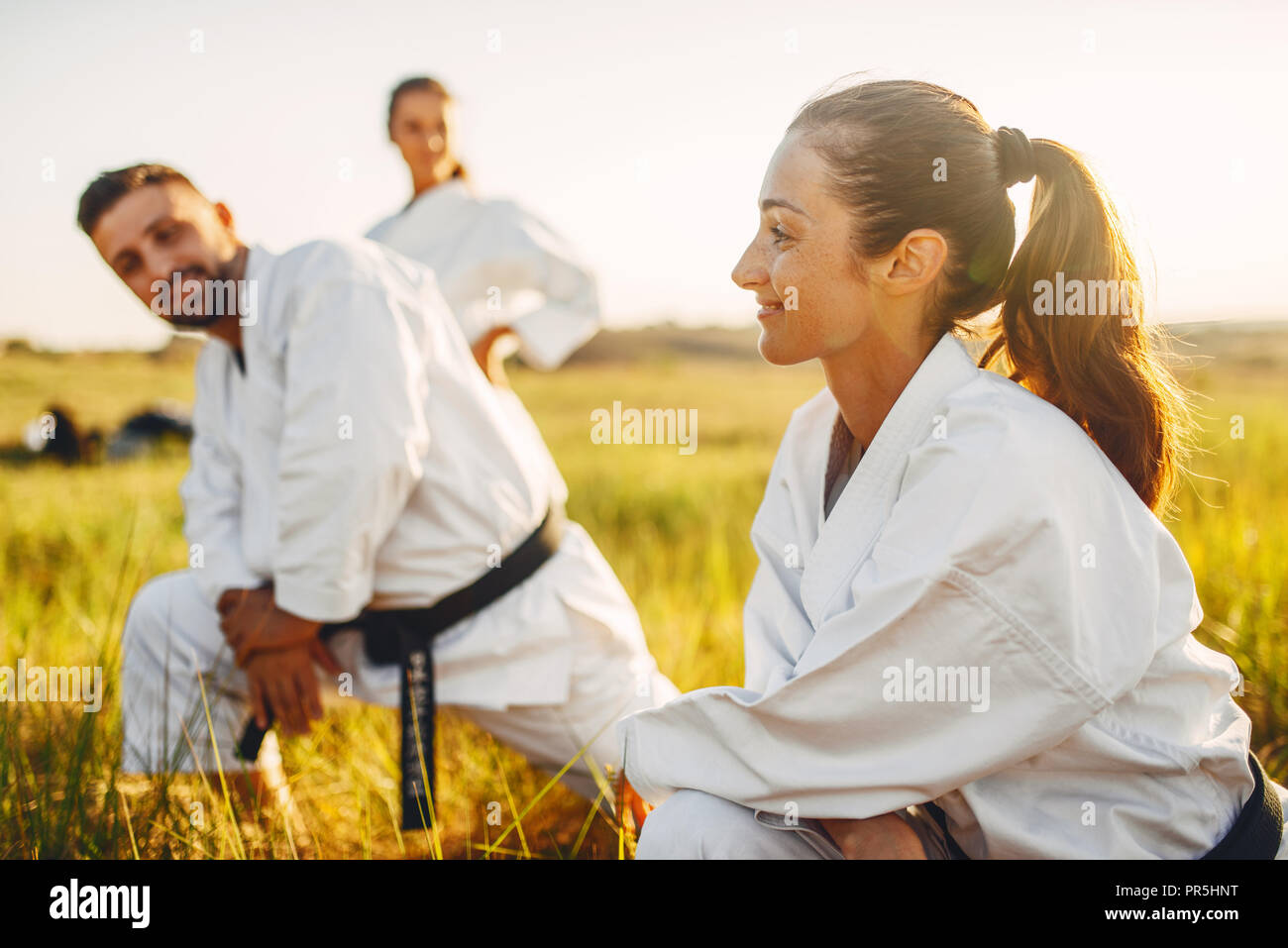 Two female karate with male instructor on training in summer field ...