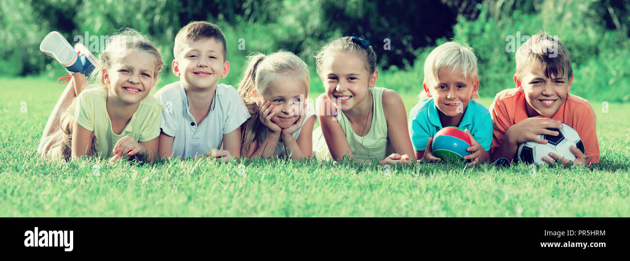 portrait of smiling american children lying on grass in park and ...
