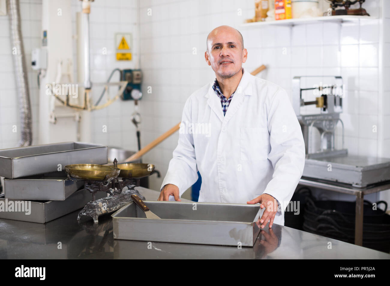 Adult male standing in production workshop in white overalls Stock ...