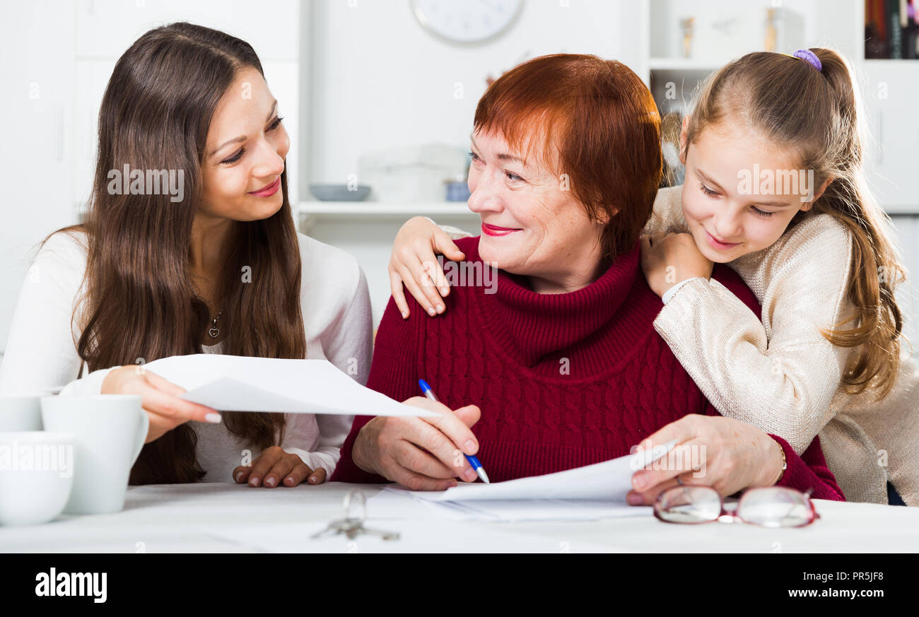 Three generations of happy family working together with documents at ...