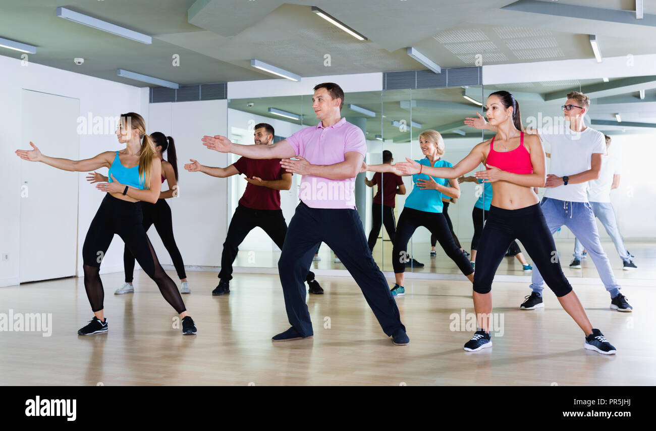 Cheerful positive men women performing modern dance in fitness studio ...