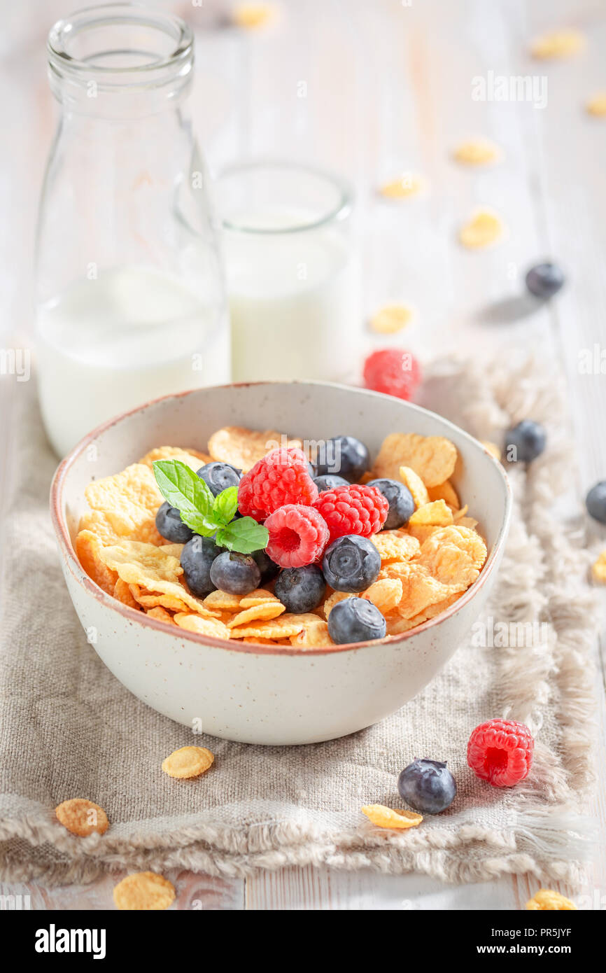 Sweet cornflakes with berry fruits and milk on rustic table Stock Photo ...