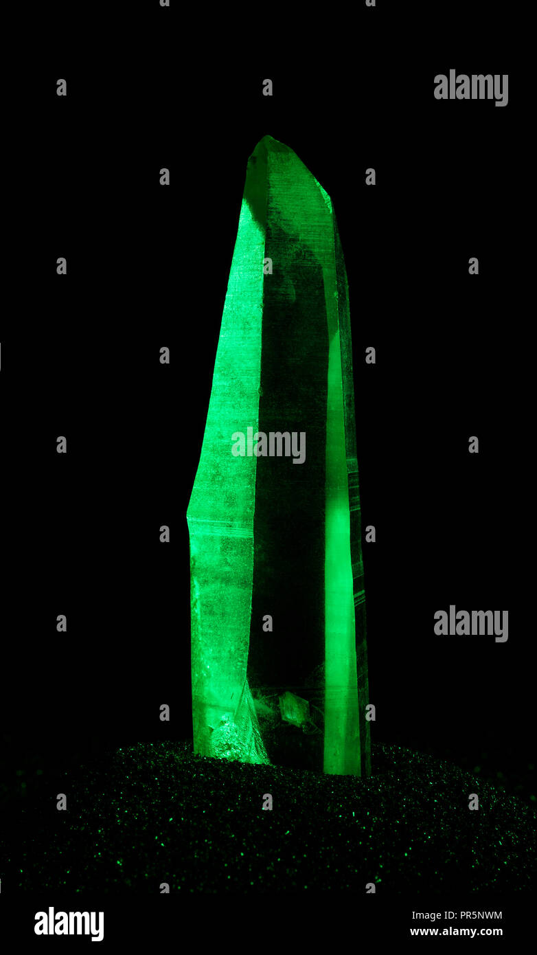 Quartz crystal in dark sand with a green light Stock Photo - Alamy