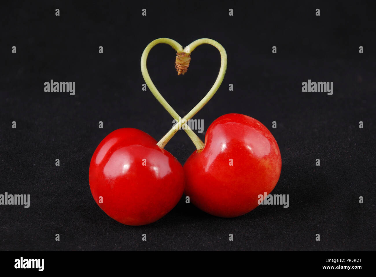 Pair of sweet cherry fruits with heart shaped stem isolated on black ...
