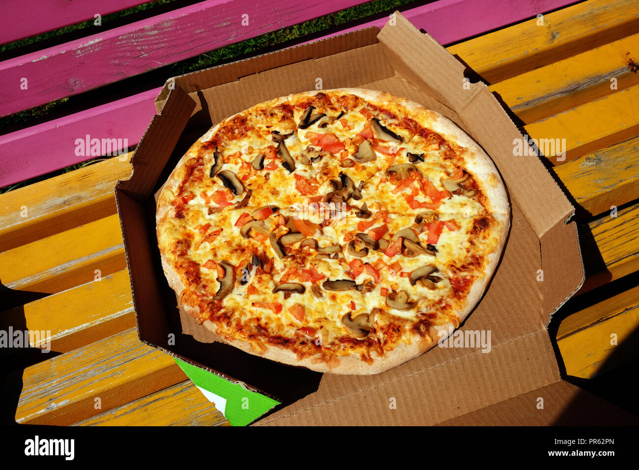 Pizza in a box, at colorful bench Stock Photo - Alamy