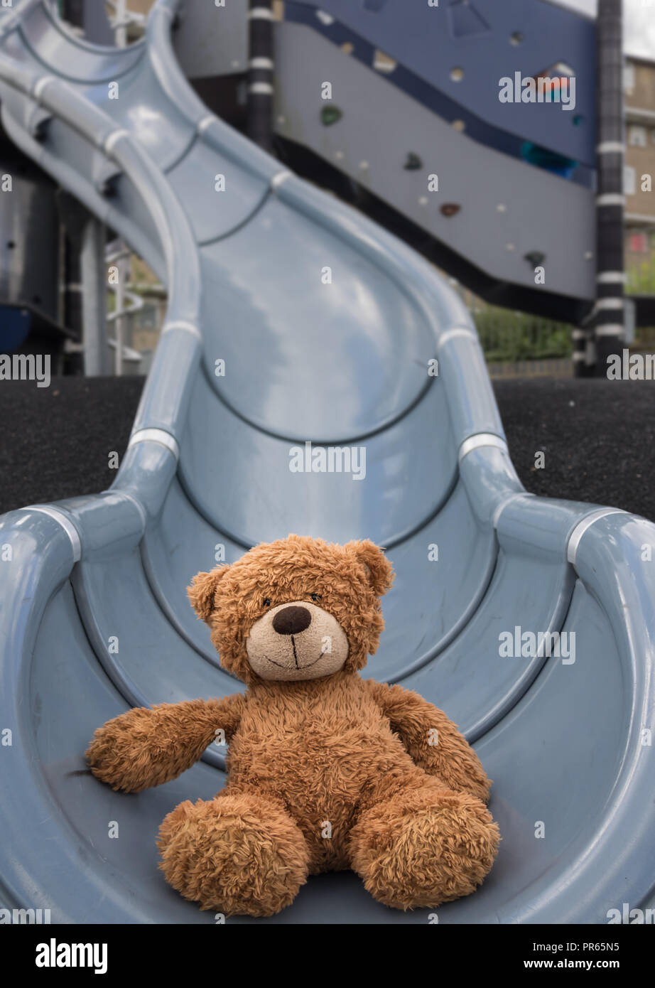 Cute little brown teddy bear at the bottom of big outdoor slide in the ...