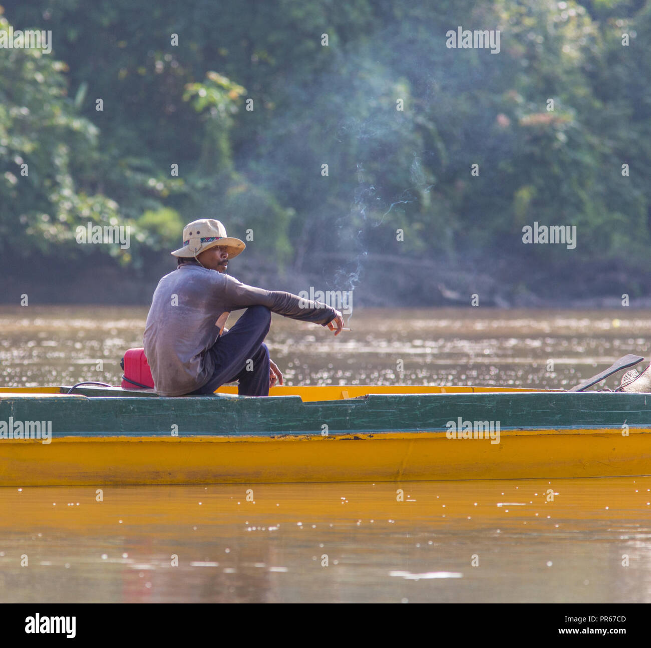 A fisherman enjoying a quiet smoke on the peaceful Kinabatangan River ...
