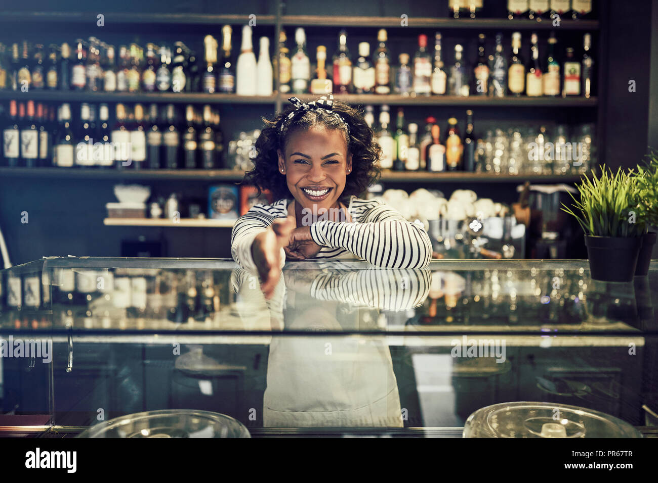 Smiling young African entrepreneur standing behind the counter a trendy ...