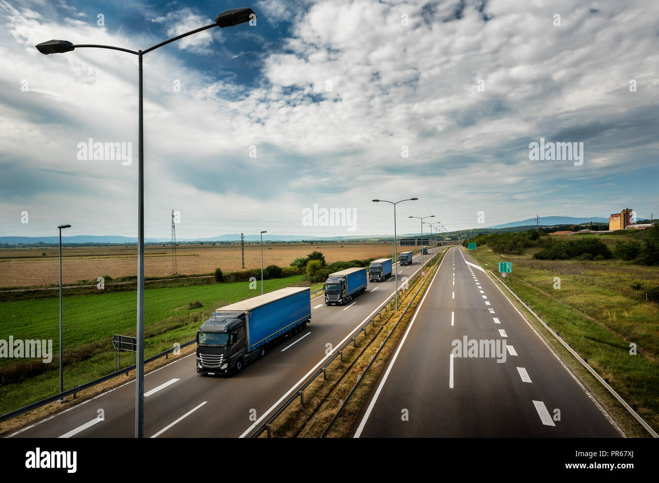 Caravan or convoy of blue lorry trucks in line on a country highway ...
