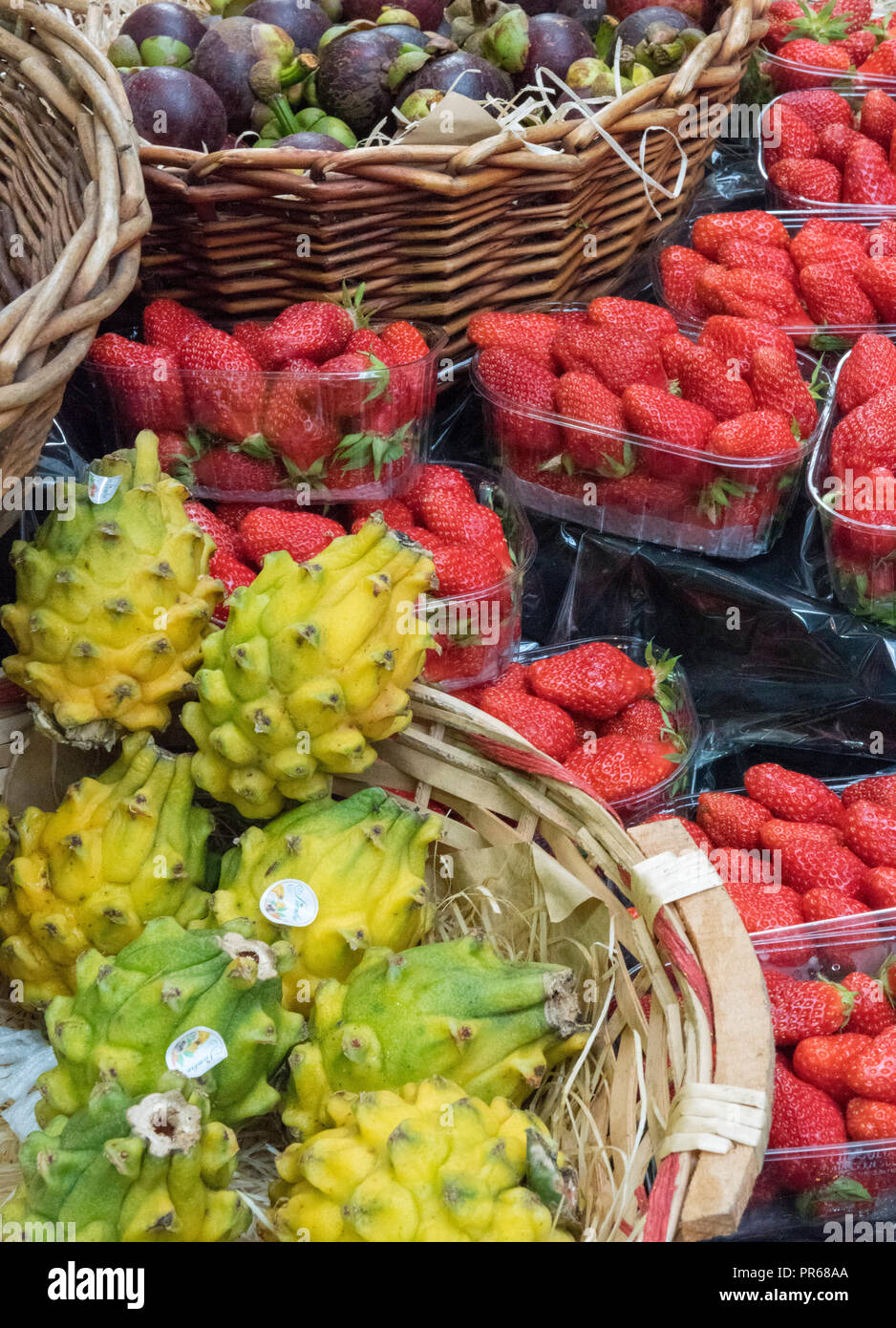 a selection of colourful fresh fruits on display in baskets and crates ...