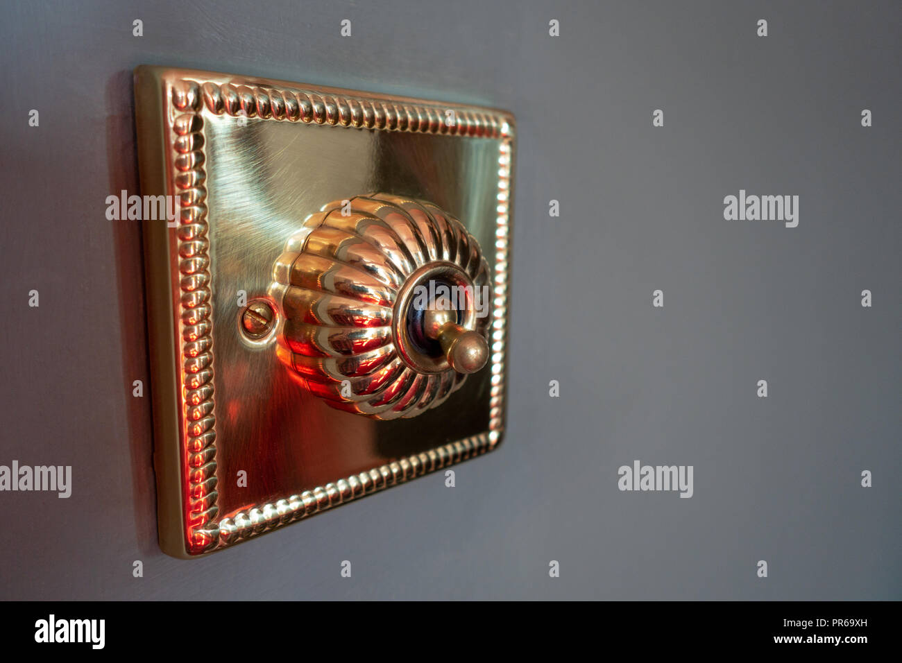 Brass Lightswitch fitting on a house wall Stock Photo - Alamy