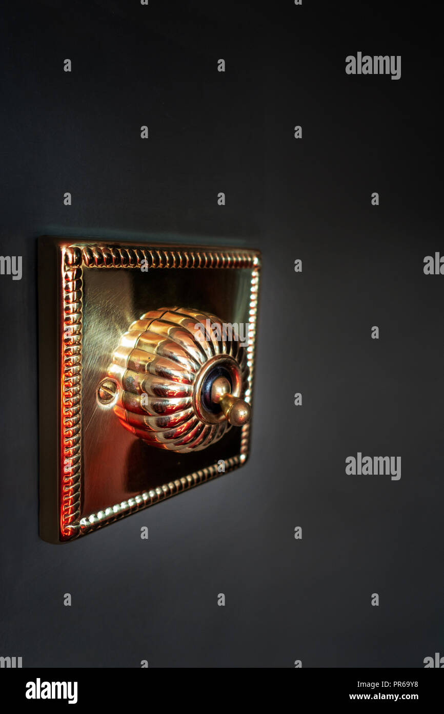 Brass Lightswitch fitting on a house wall Stock Photo - Alamy