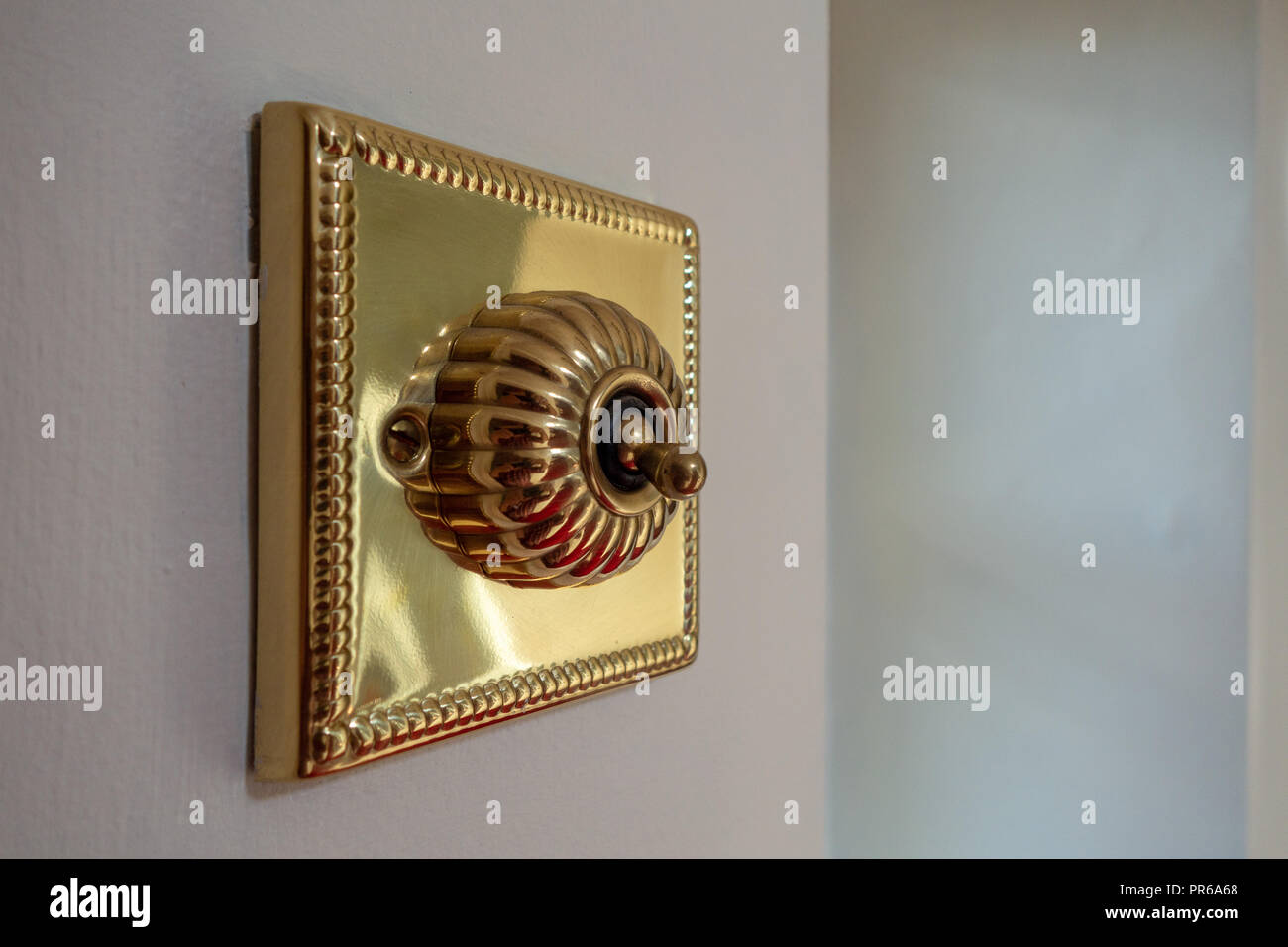 Brass Lightswitch fitting on a house wall Stock Photo - Alamy