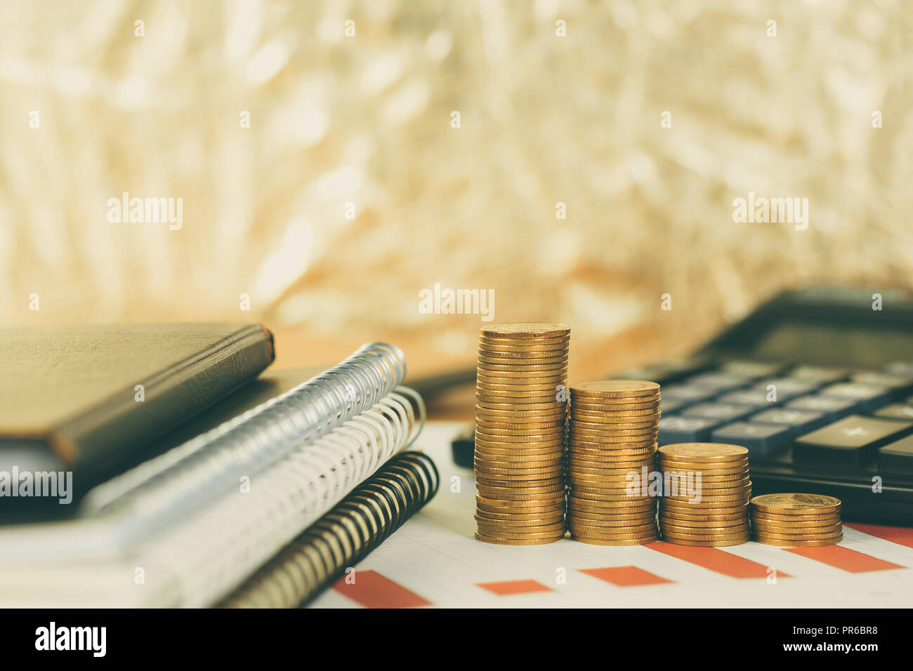 Coin stack and financial graph paper sheet with calculator on working ...