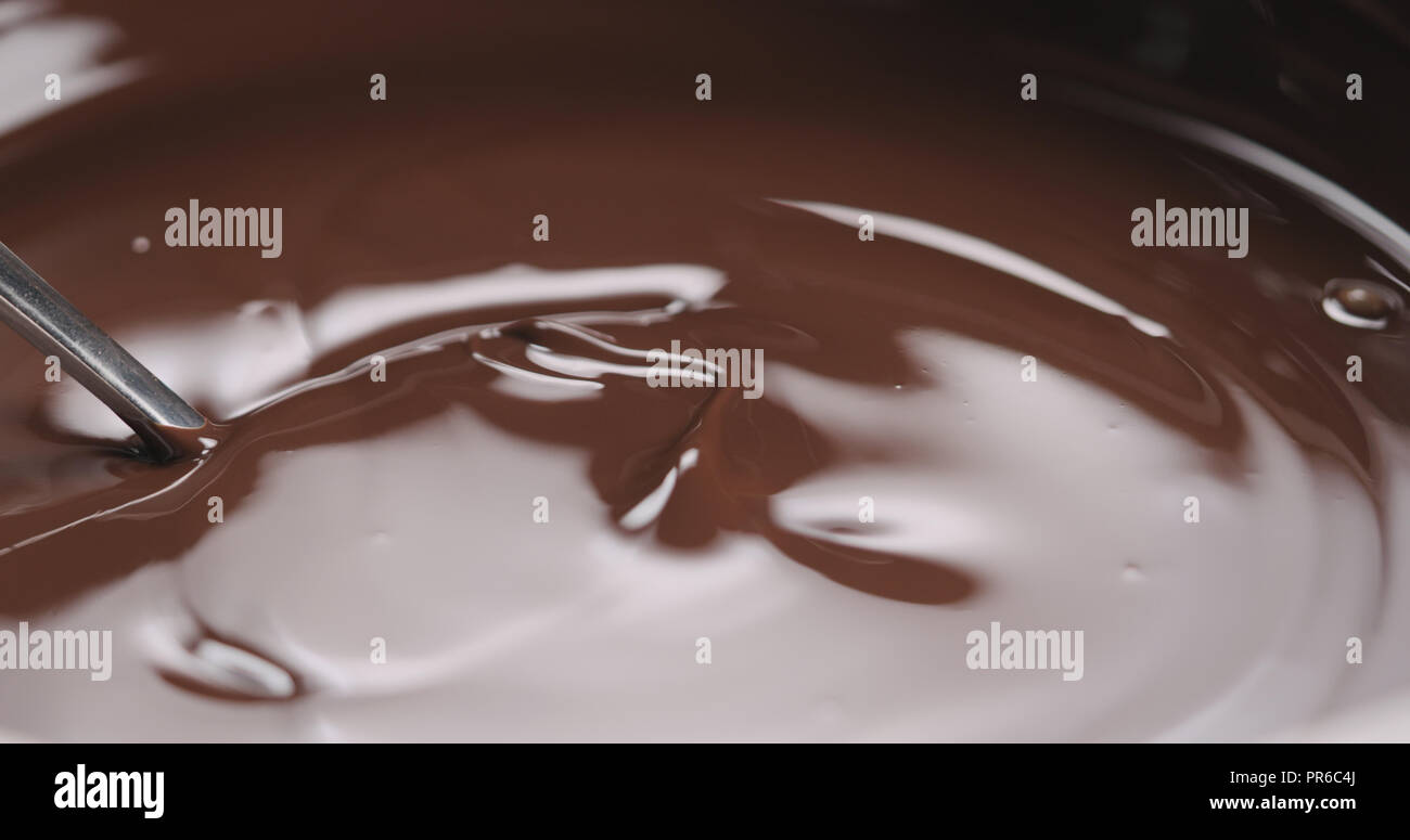 closeup stirring melted dark chocolate with spoon Stock Photo - Alamy