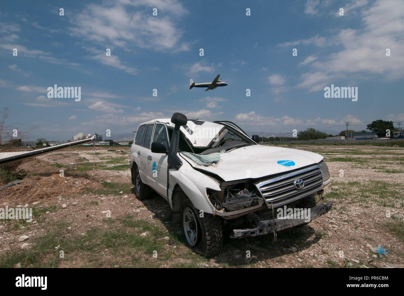 An airplane flying over a smashed UN vehicle in MInustah UN base ...