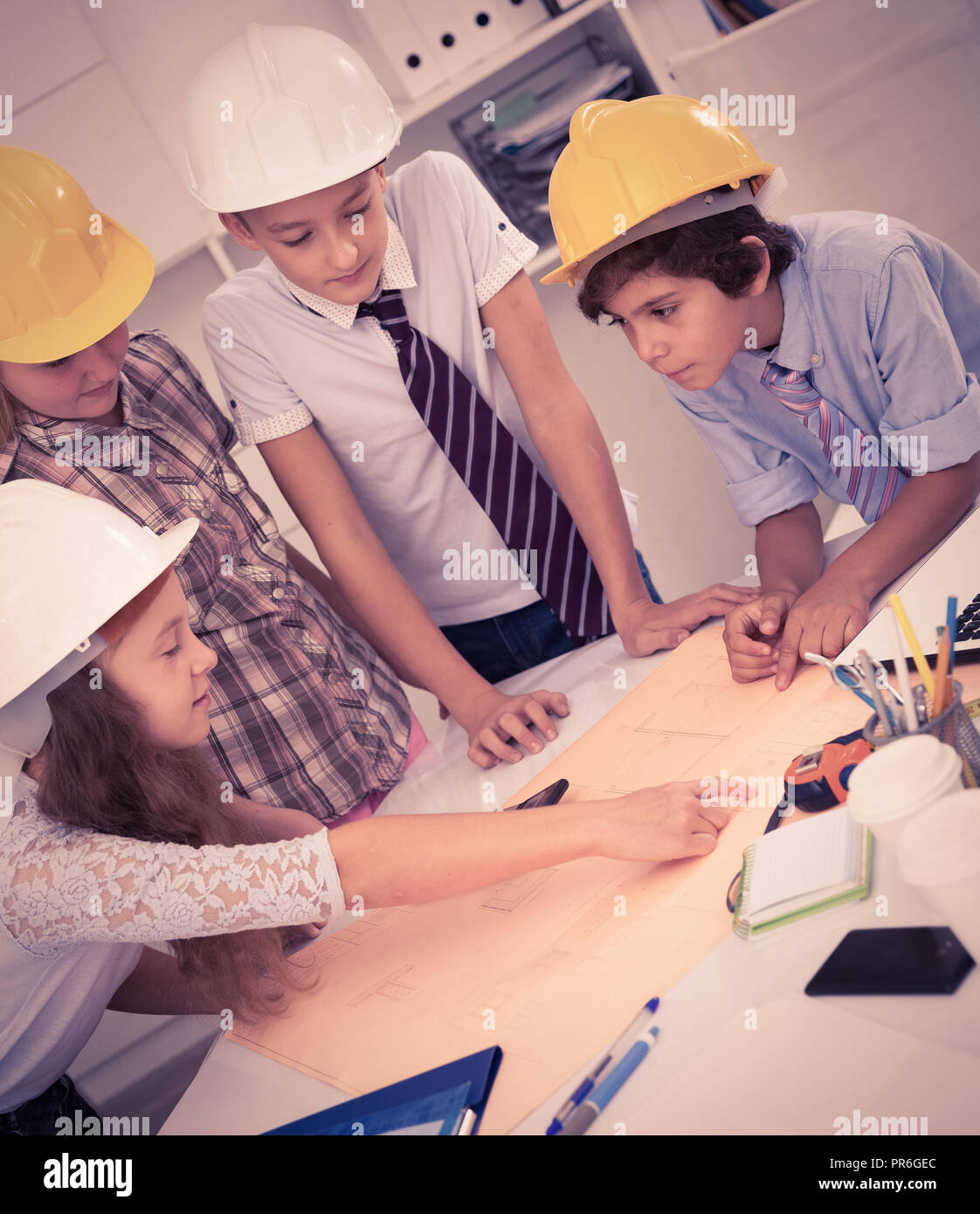Teens in color helmet engineers discussing draft at the table Stock ...
