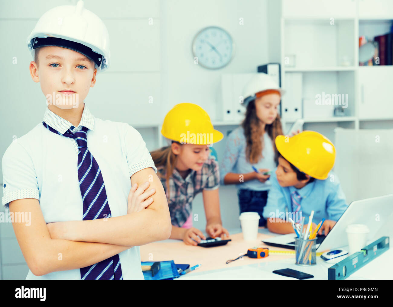 Teenager boy engineer and children with plan and notebook in the office ...