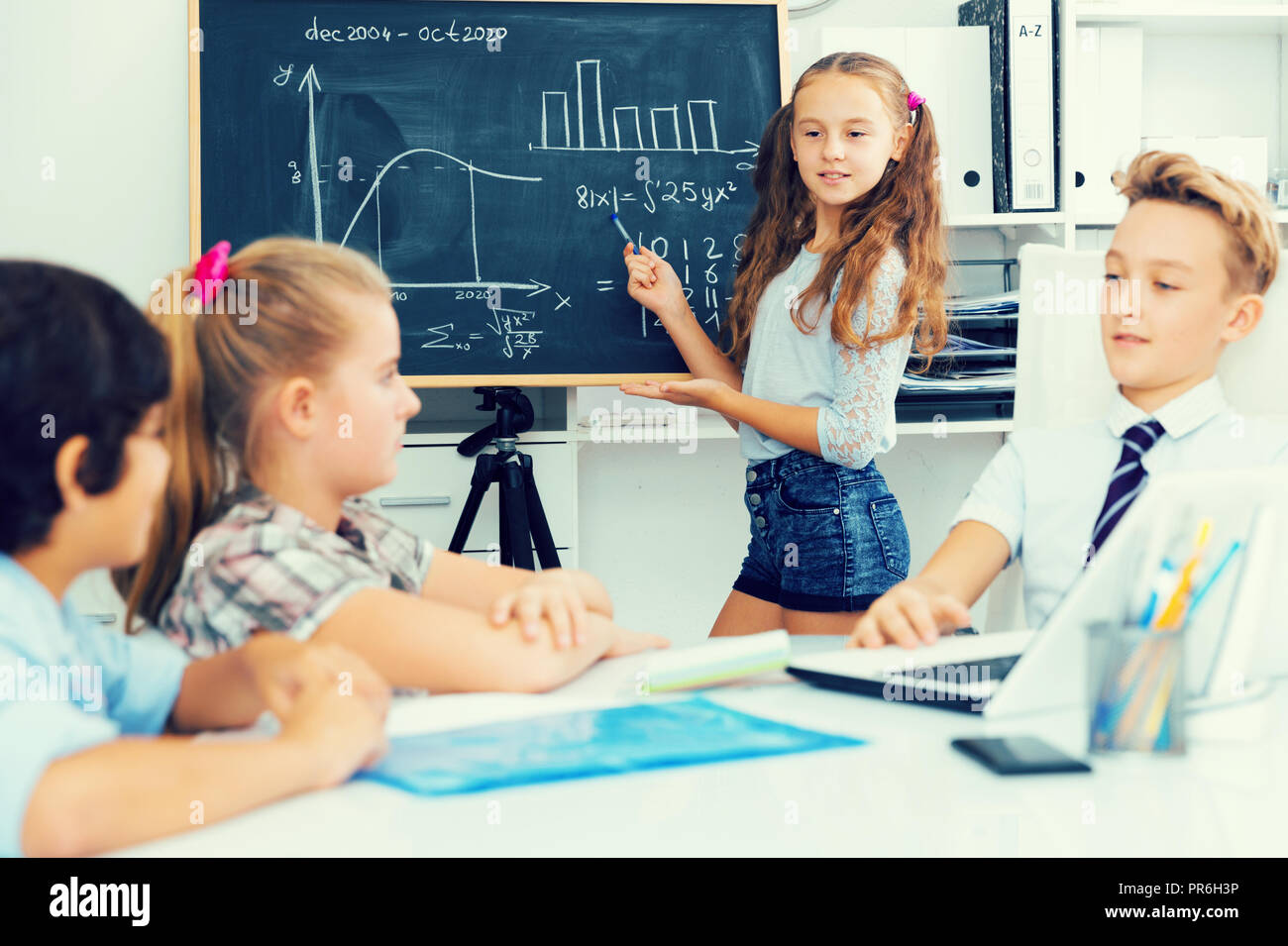 Girl discussing about mathematical formulas with friends in classroom ...
