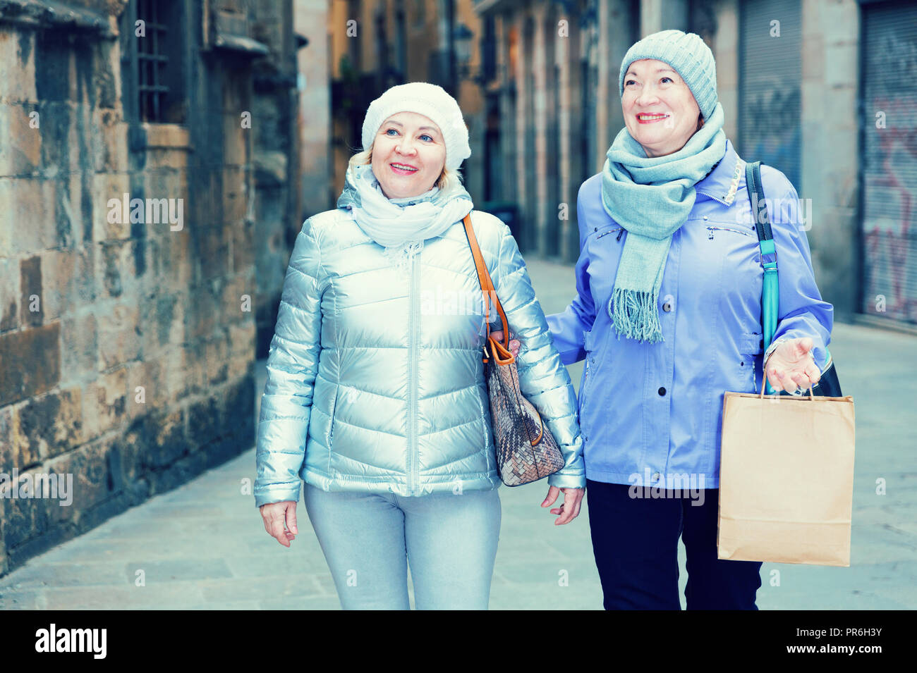Senior woman with female friend walking together along autumn city ...