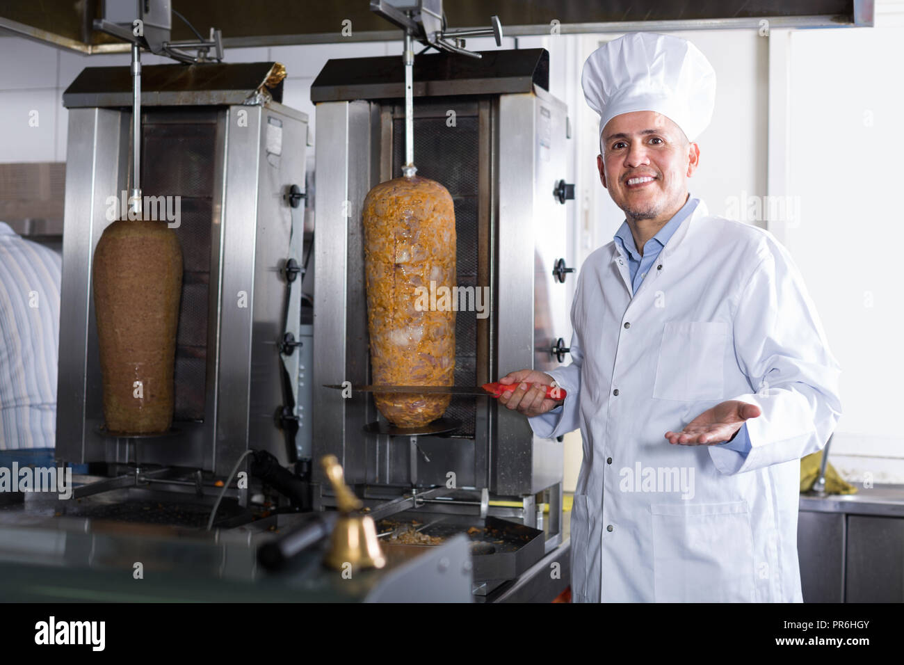 smiling man chef in uniform serving fresh kebab in restaurant Stock ...