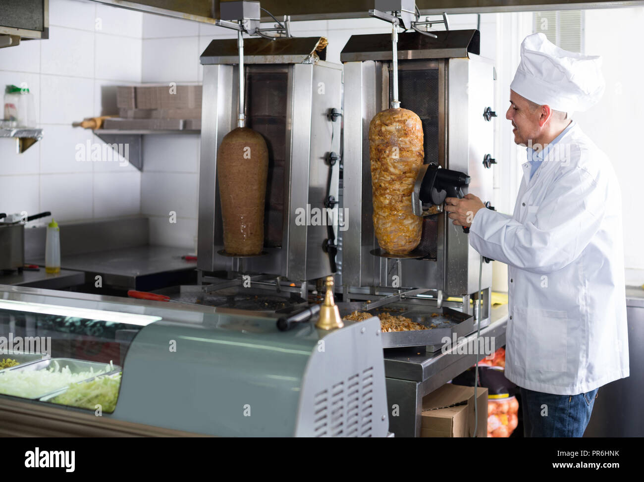 happy russian mature man chef wearing uniform cutting meat for kebab on ...