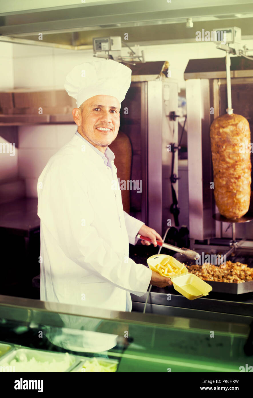 smiling mature man chef 50-55 years old serving fresh kebab in ...