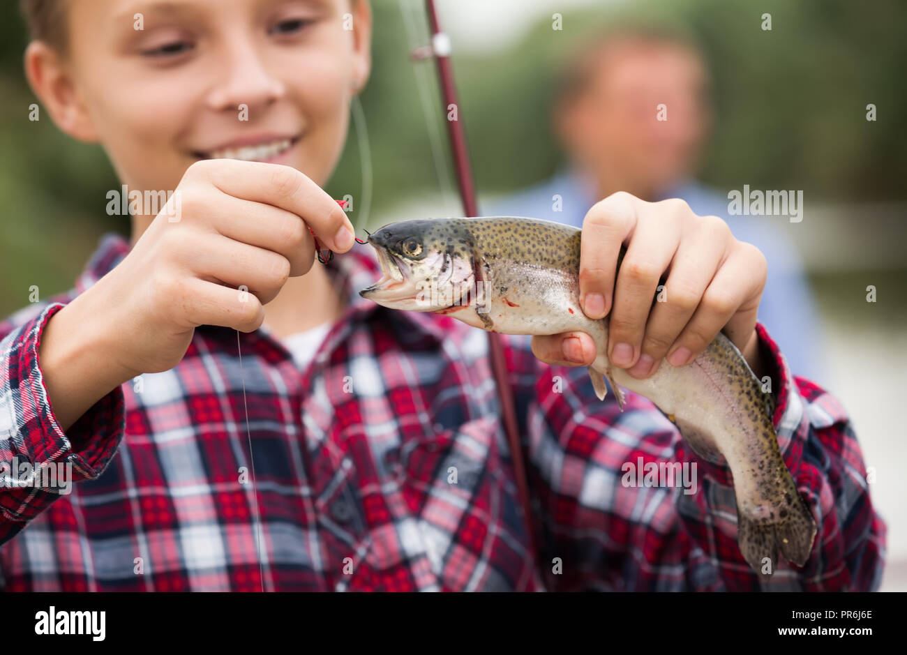 Happy teenage boy releasing catch on hook fish on vacation Stock Photo ...