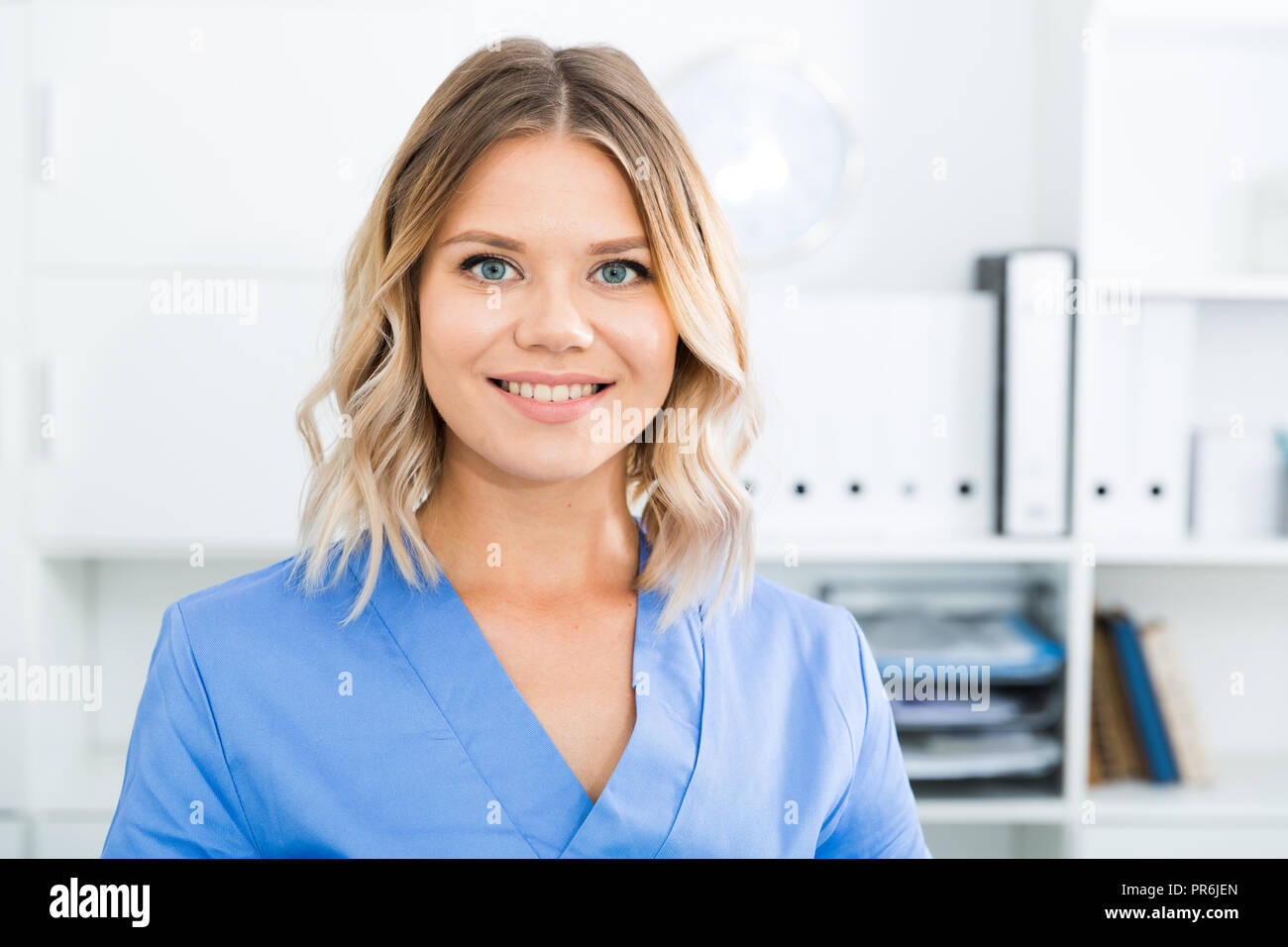Kindly woman in doctor's uniform greets visitors at modern office Stock ...