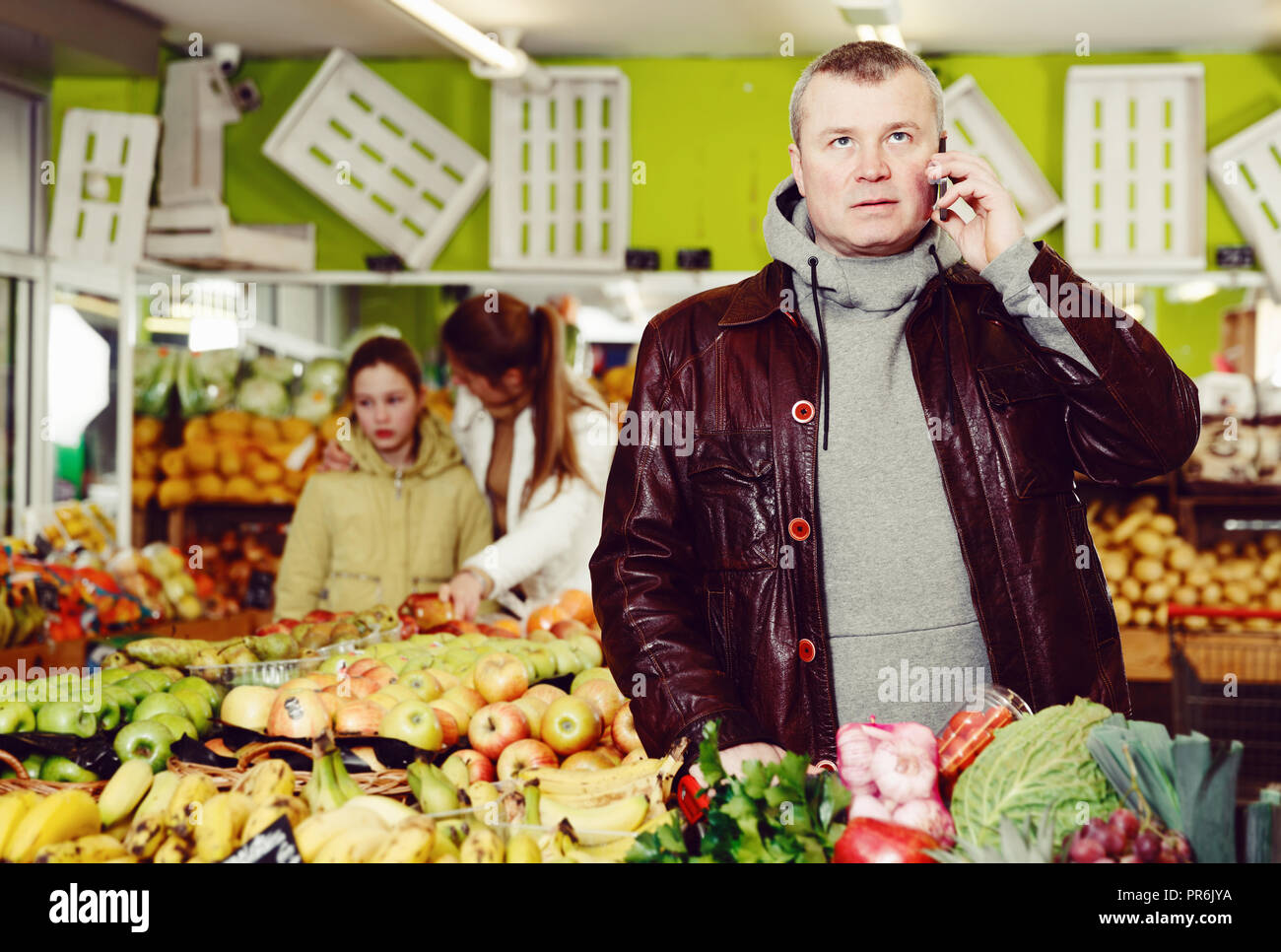 Man customer speaking by phone in vegetable and fruit store during ...