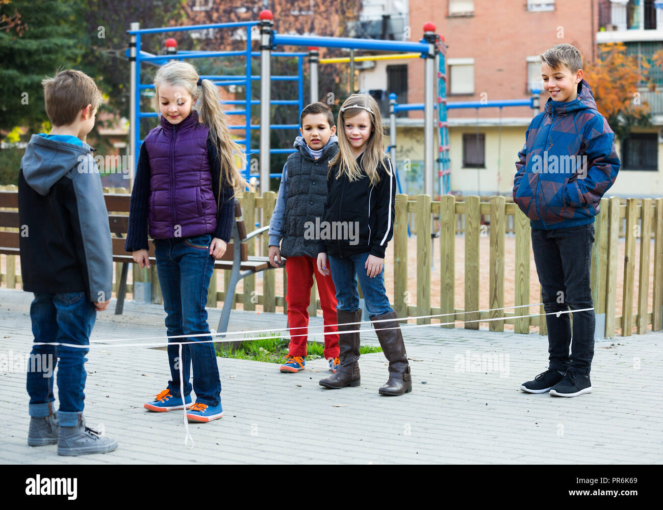 Happy positive children playing rubber band jumping game and laughing ...