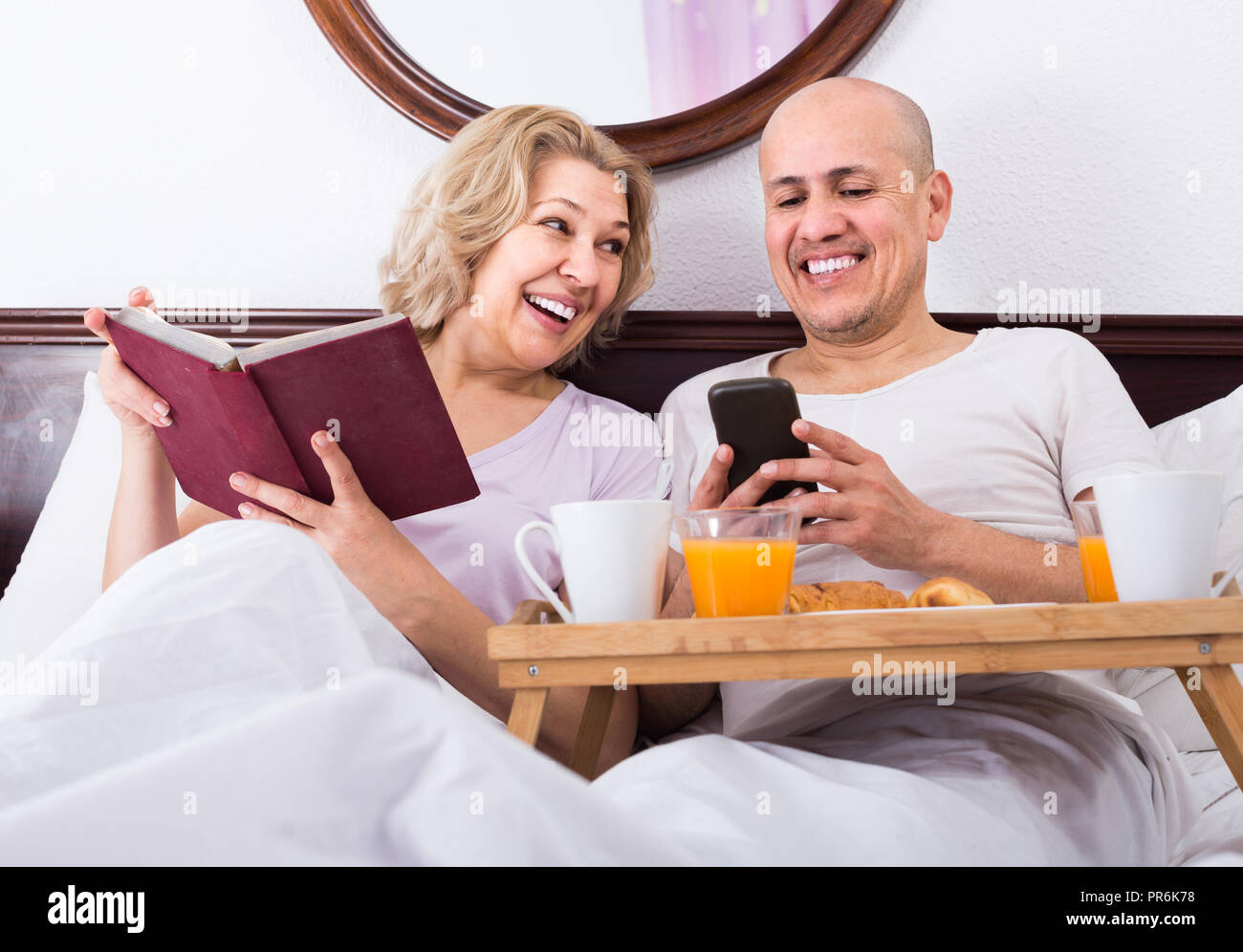 Happy russian man showing girlfriend something on book during breakfast ...