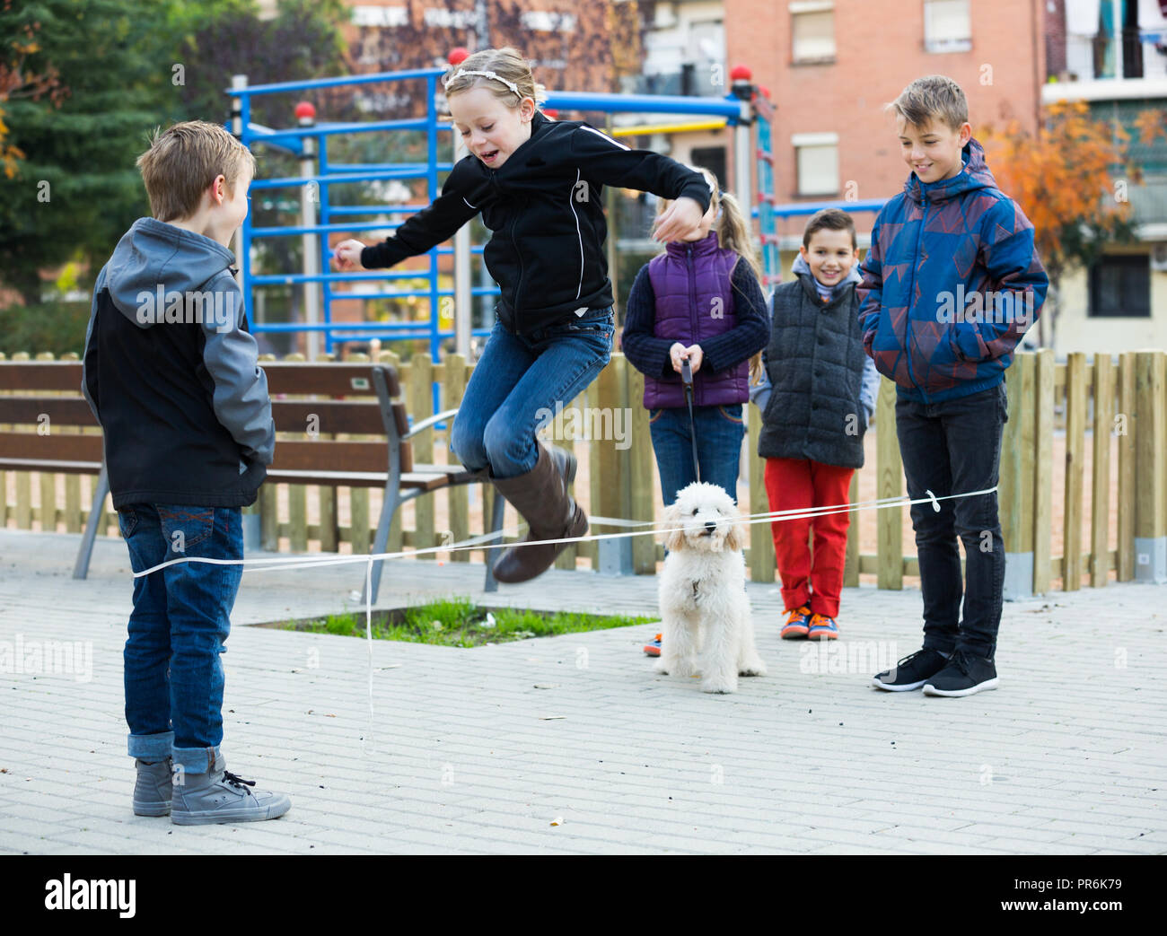 Happy caucasian children playing rubber band jumping game and laughing ...