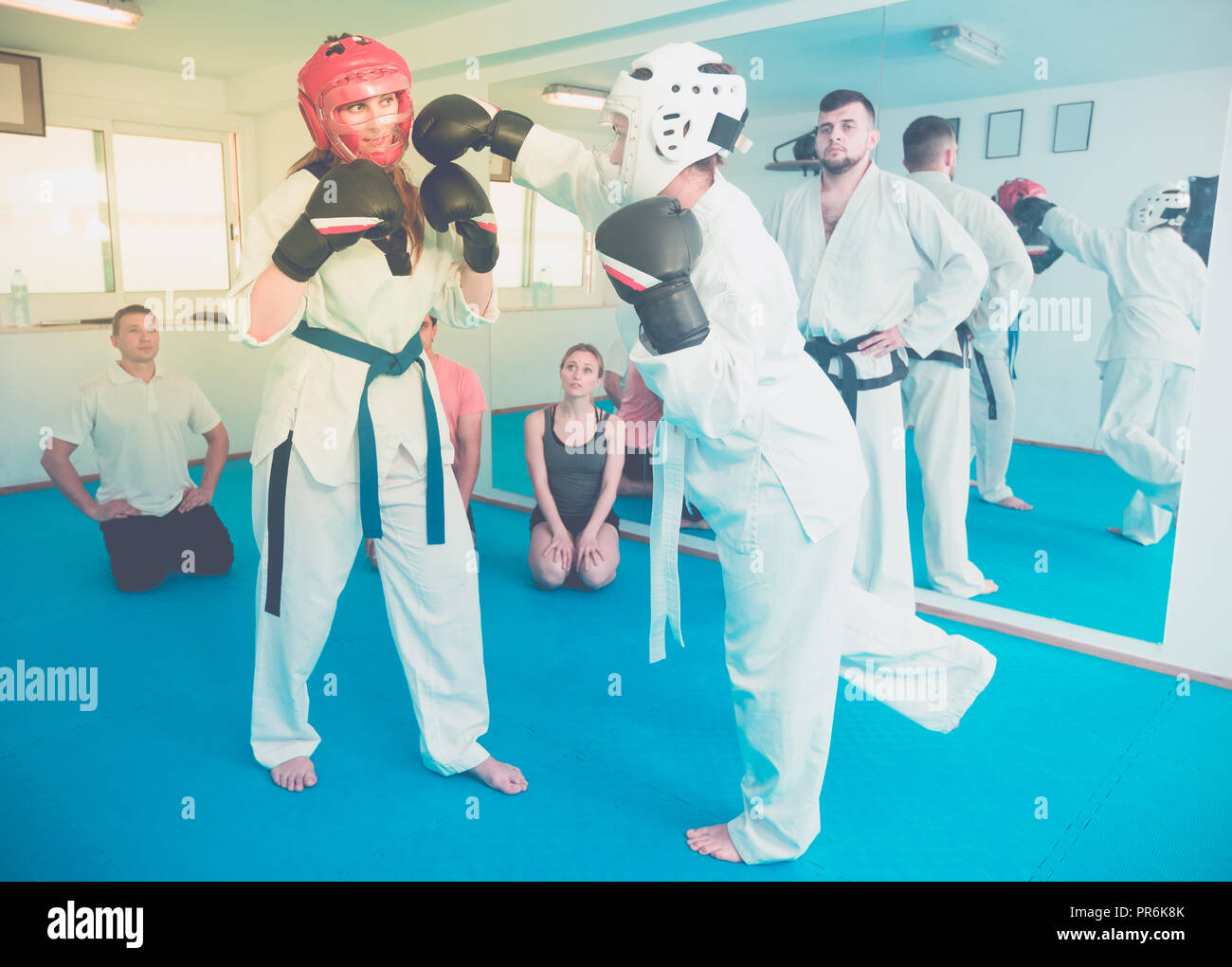 Pair of young women training new taekwondo techniques during class ...