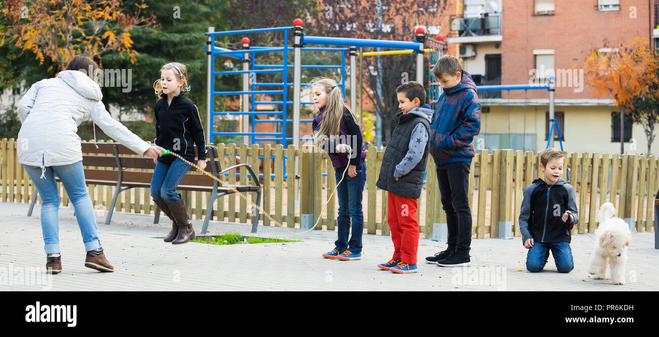 positive children playing rubber band jumping game and laughing ...