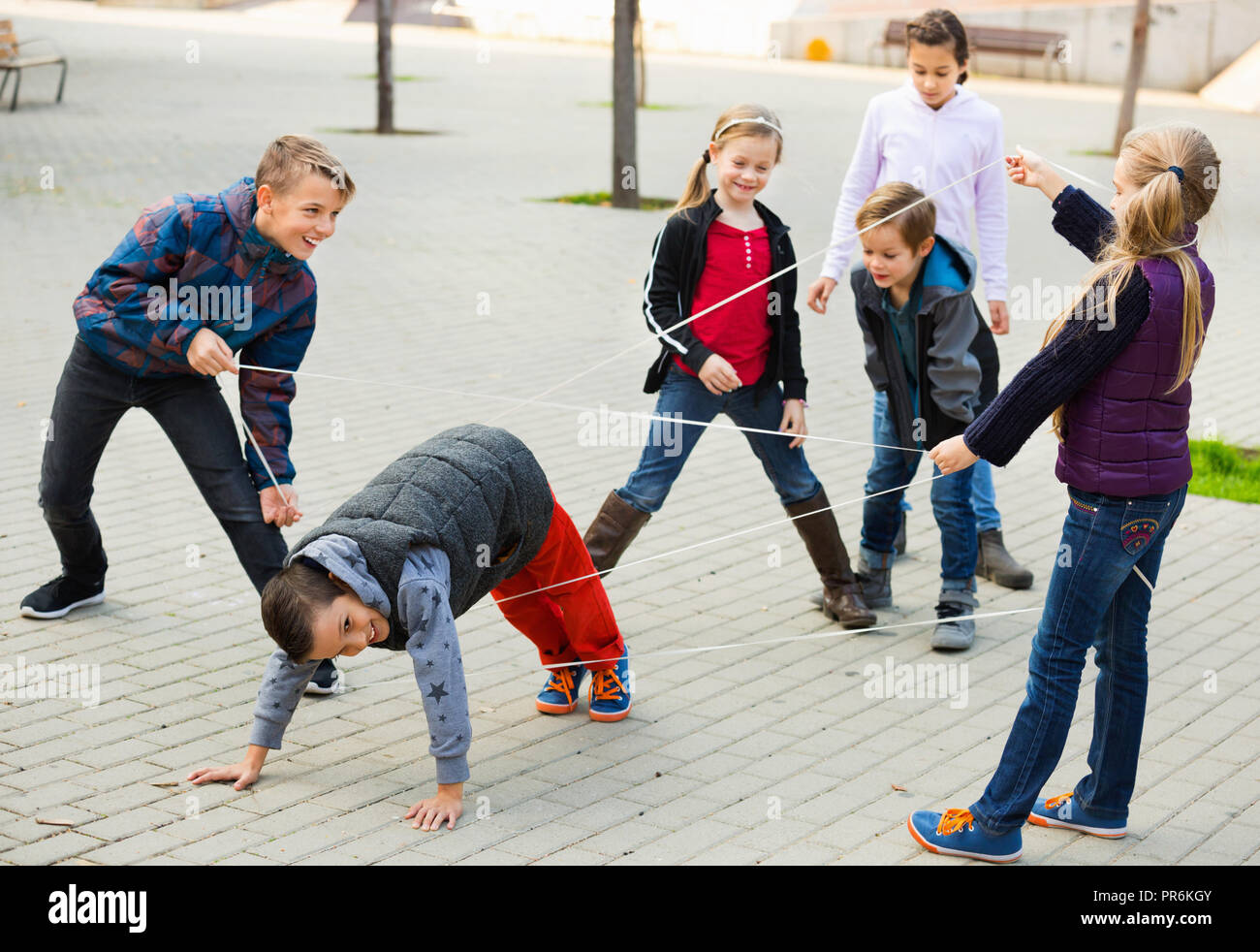 Children games. Smiling positive girl goes through the tangled rope ...