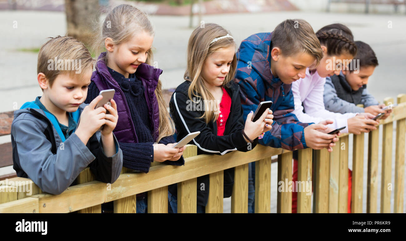 Group of children posing at urban street with mobile devices outdoors ...
