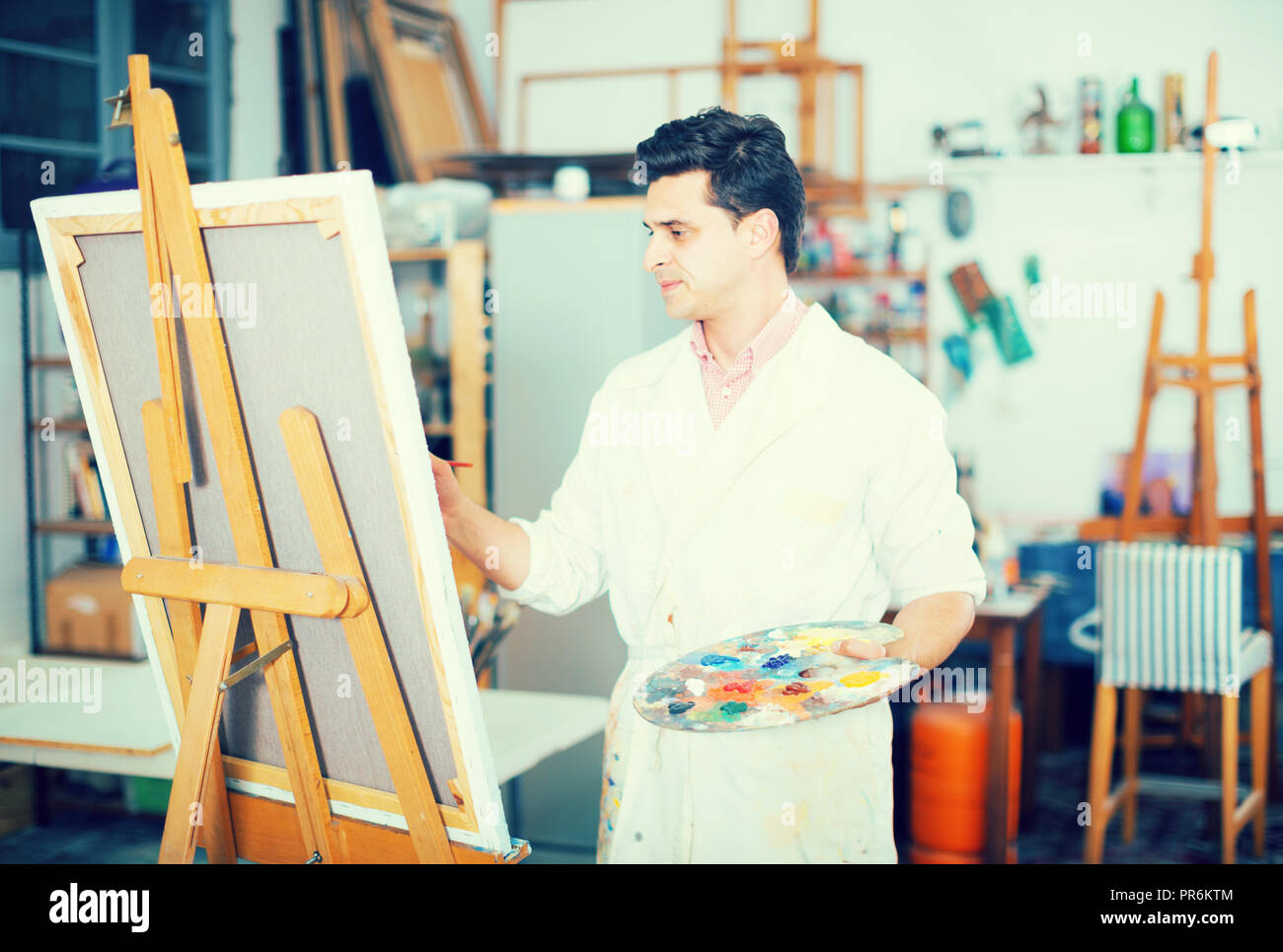Happy art painter holding artist palette and painting on canvas Stock ...