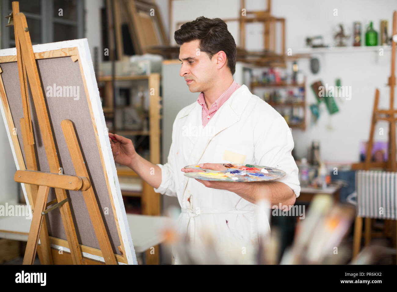 Creative male artist drawing picture with oil paints in studio Stock ...