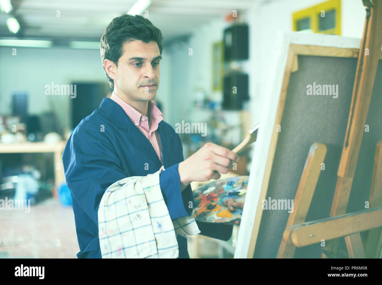 Happy art painter holding artist palette and painting on canvas Stock ...