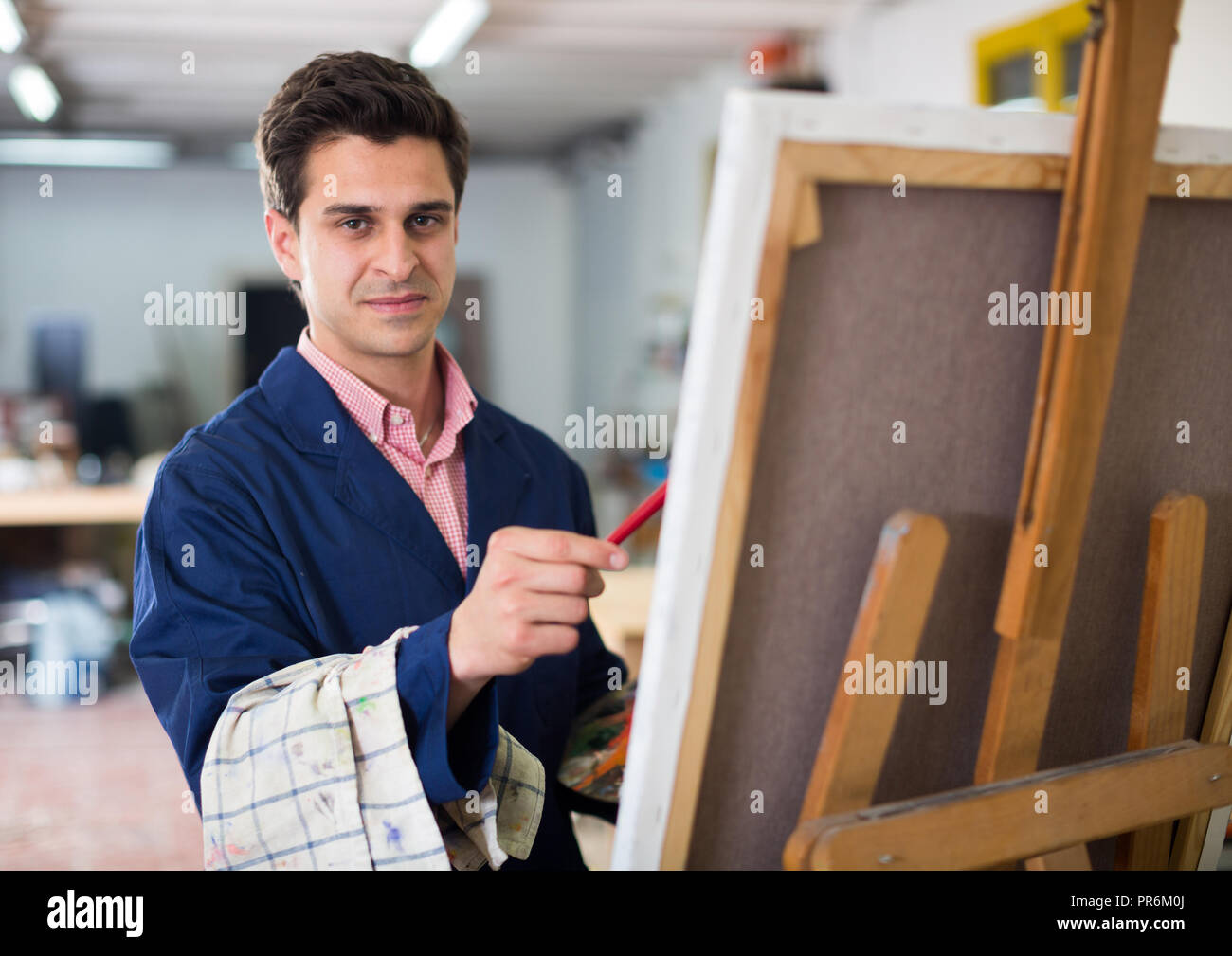 Happy art painter holding artist palette and painting on canvas Stock ...